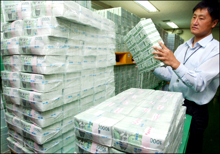 A Bank of Korea (BOK) official checks piles of 10,000... - The Korea Times