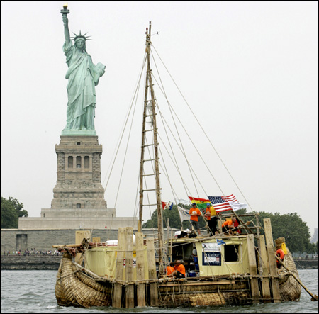 The Abora III, a boat made of reeds and wood, passes the Statue ...